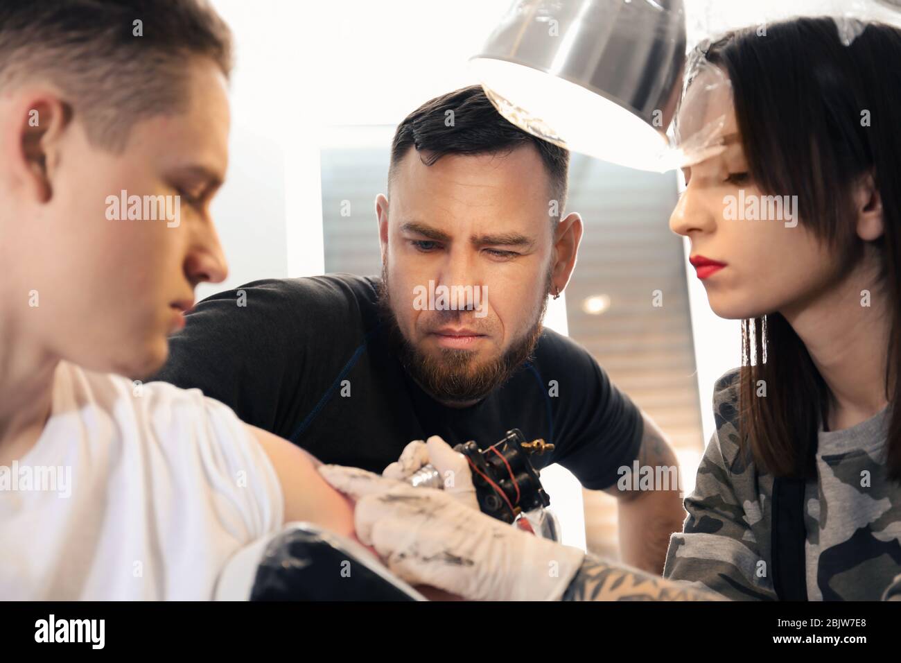 Professional tattoo master teaching young specialist in salon ...