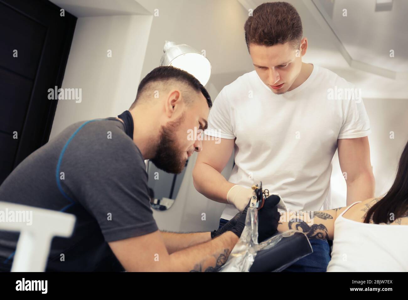 Professional tattoo master teaching young specialist in salon ...