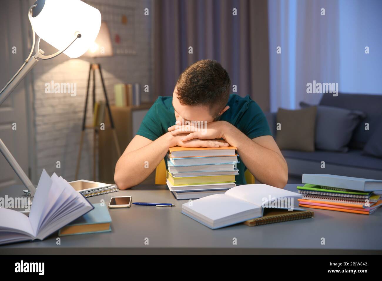 Tired student sleeping on stack of books at table indoors Stock Photo ...