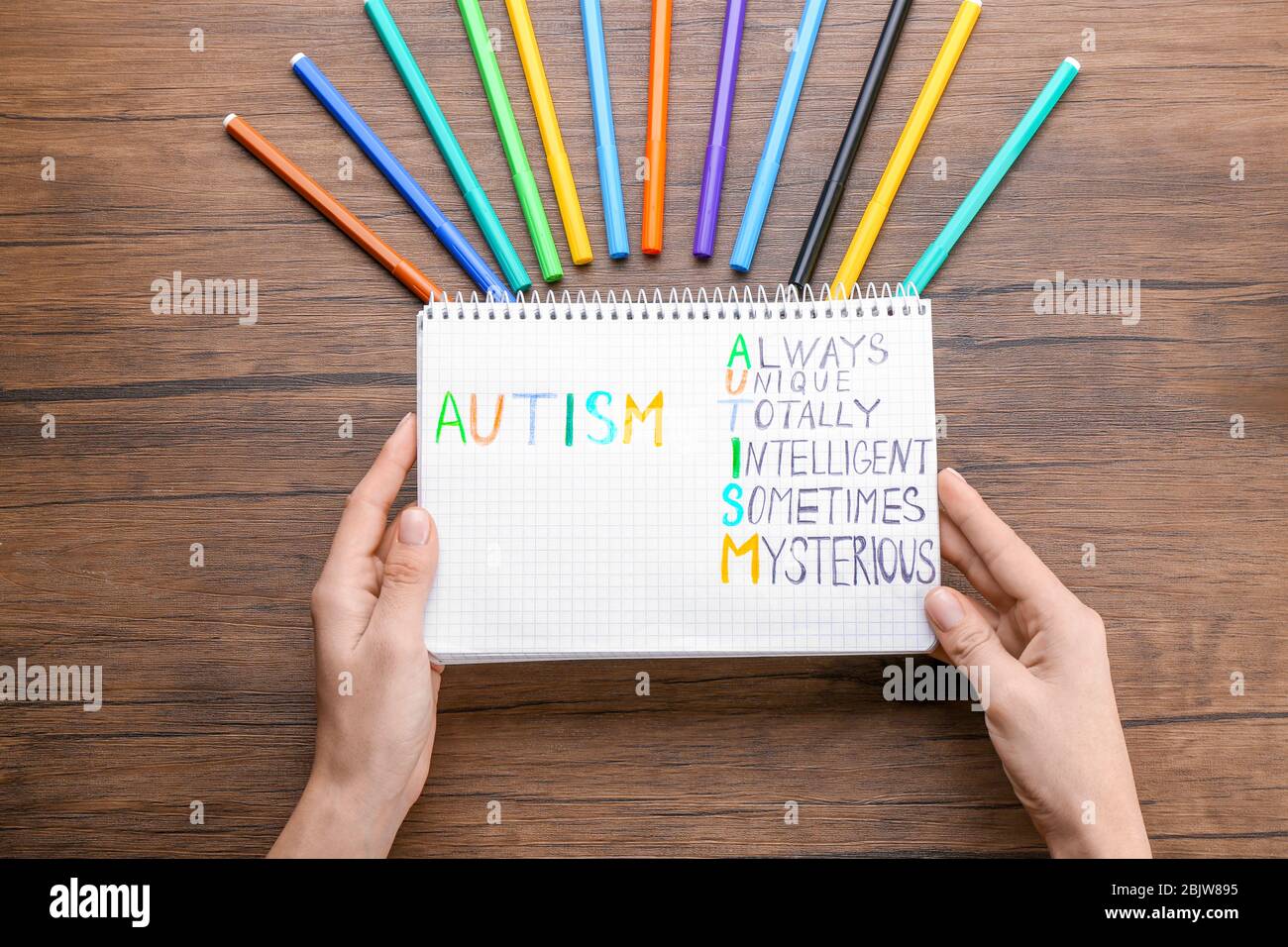 Woman holding notebook with abbreviation expansion of word "Autism" on ...