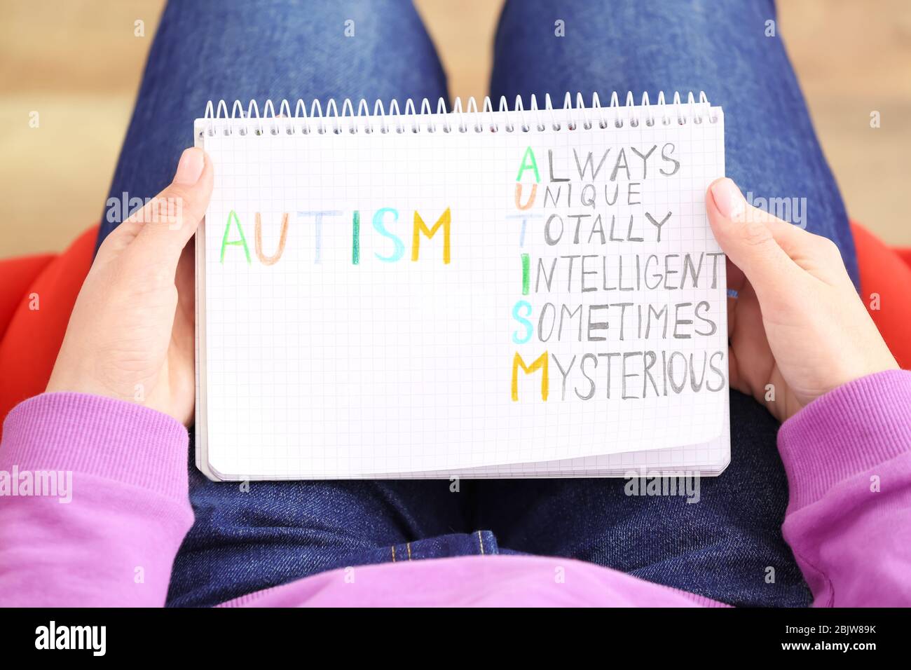 Woman holding notebook with abbreviation expansion of word "Autism ...