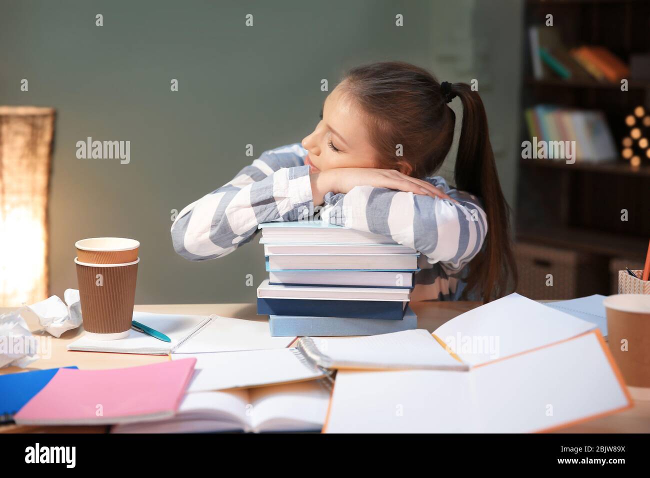 Tired student sleeping on stack of books at table indoors Stock Photo ...