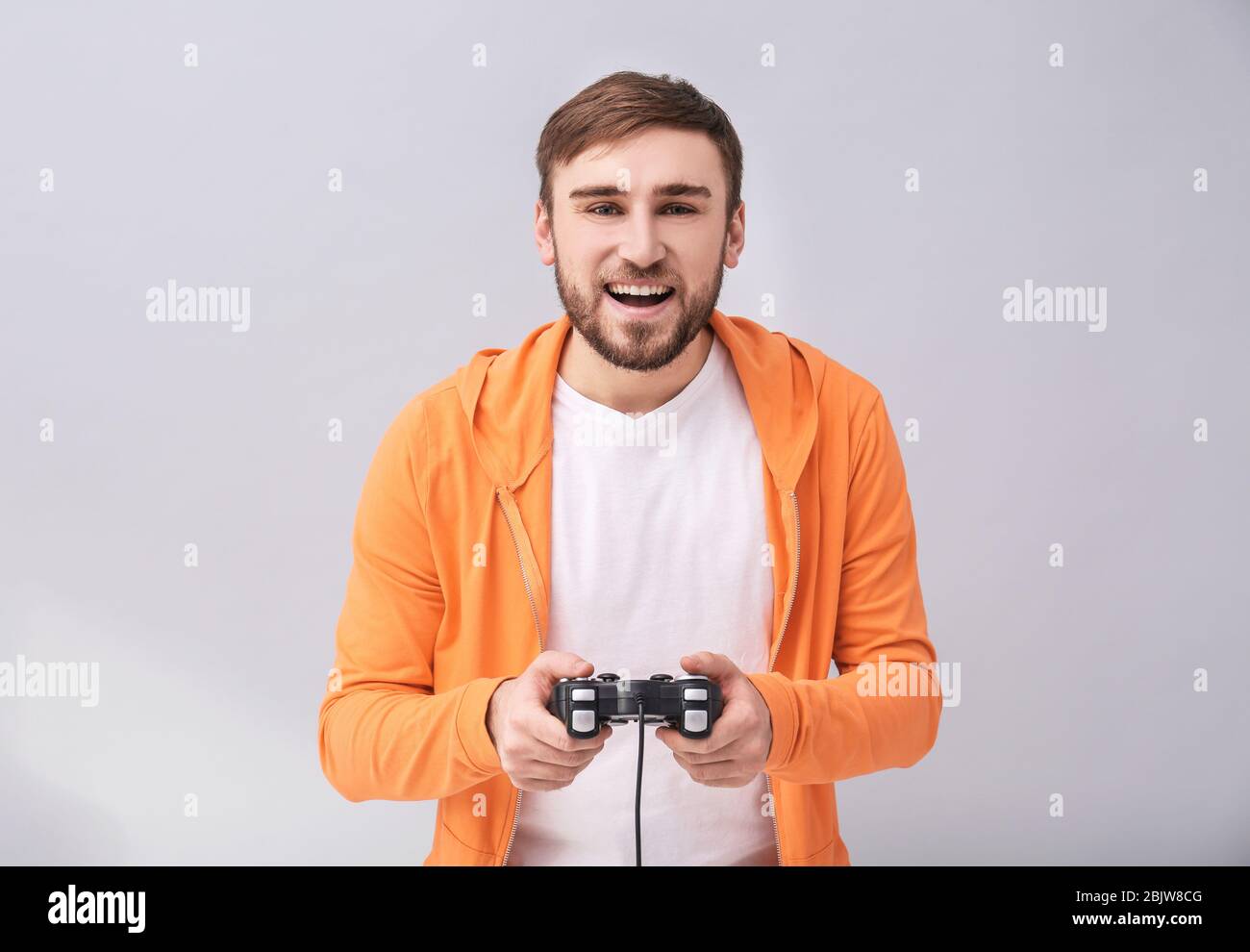 Happy man with video game controller on grey background Stock Photo - Alamy