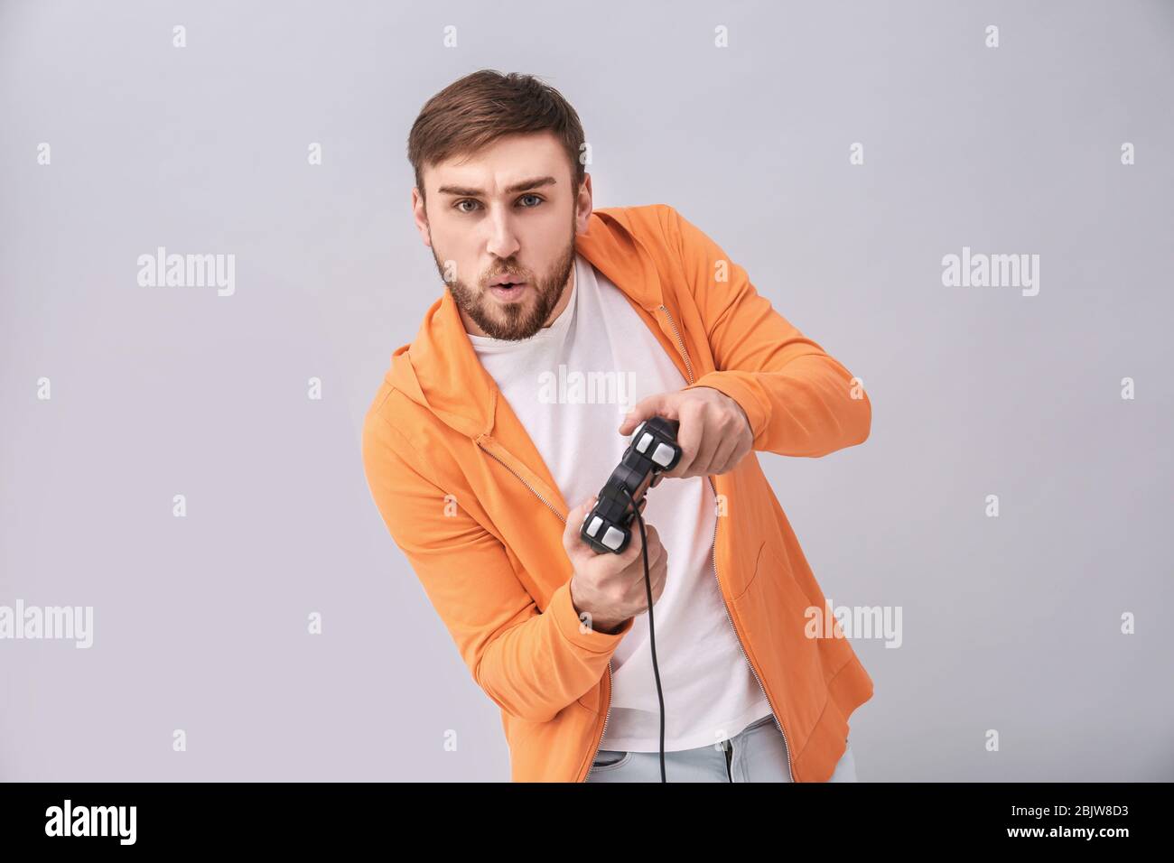 Emotional man with video game controller on grey background Stock Photo ...