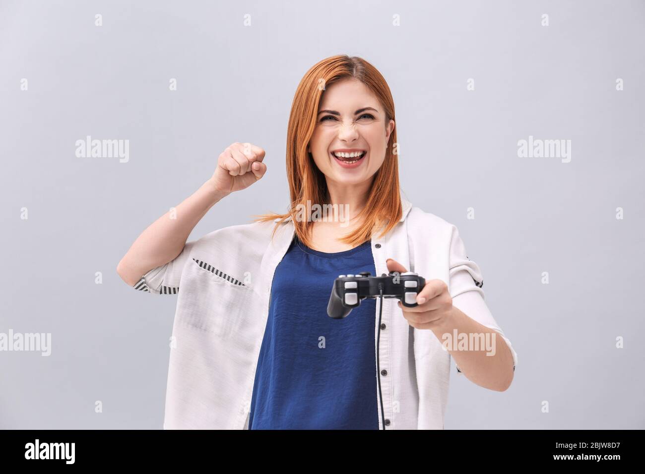 Emotional woman with video game controller on grey background Stock ...