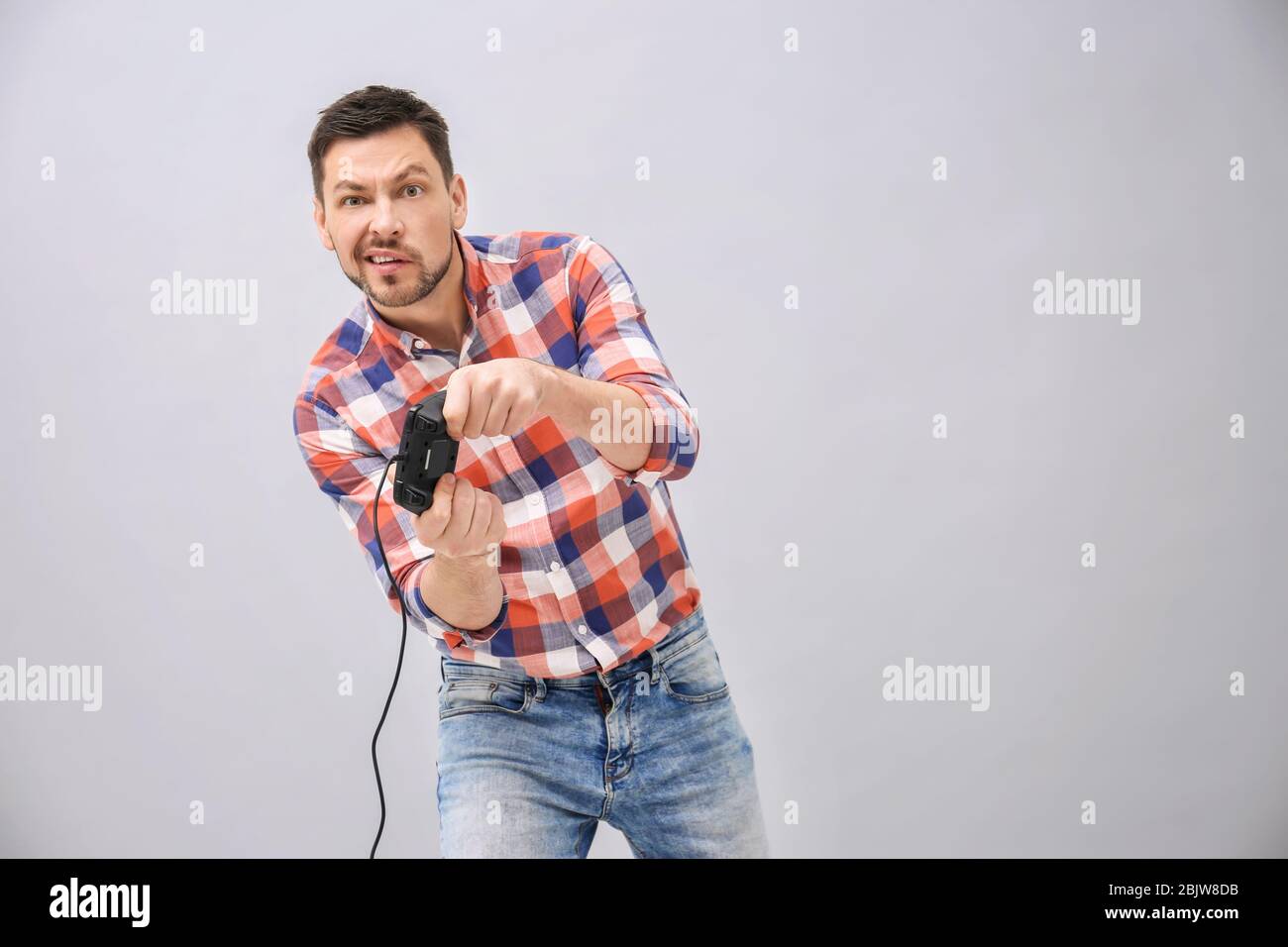 Emotional man with video game controller on grey background Stock Photo ...