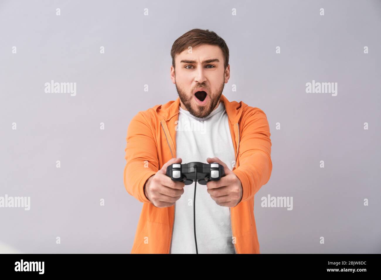 Emotional man with video game controller on grey background Stock Photo ...