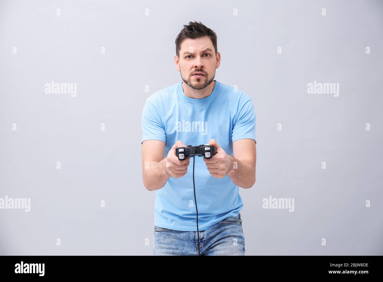 Emotional man with video game controller on grey background Stock Photo ...