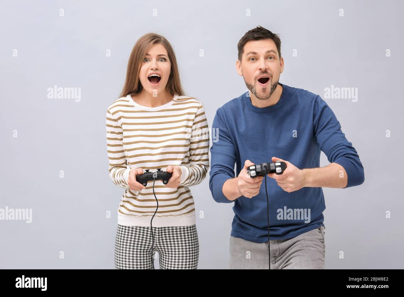 Emotional couple with video game controllers on grey background Stock ...