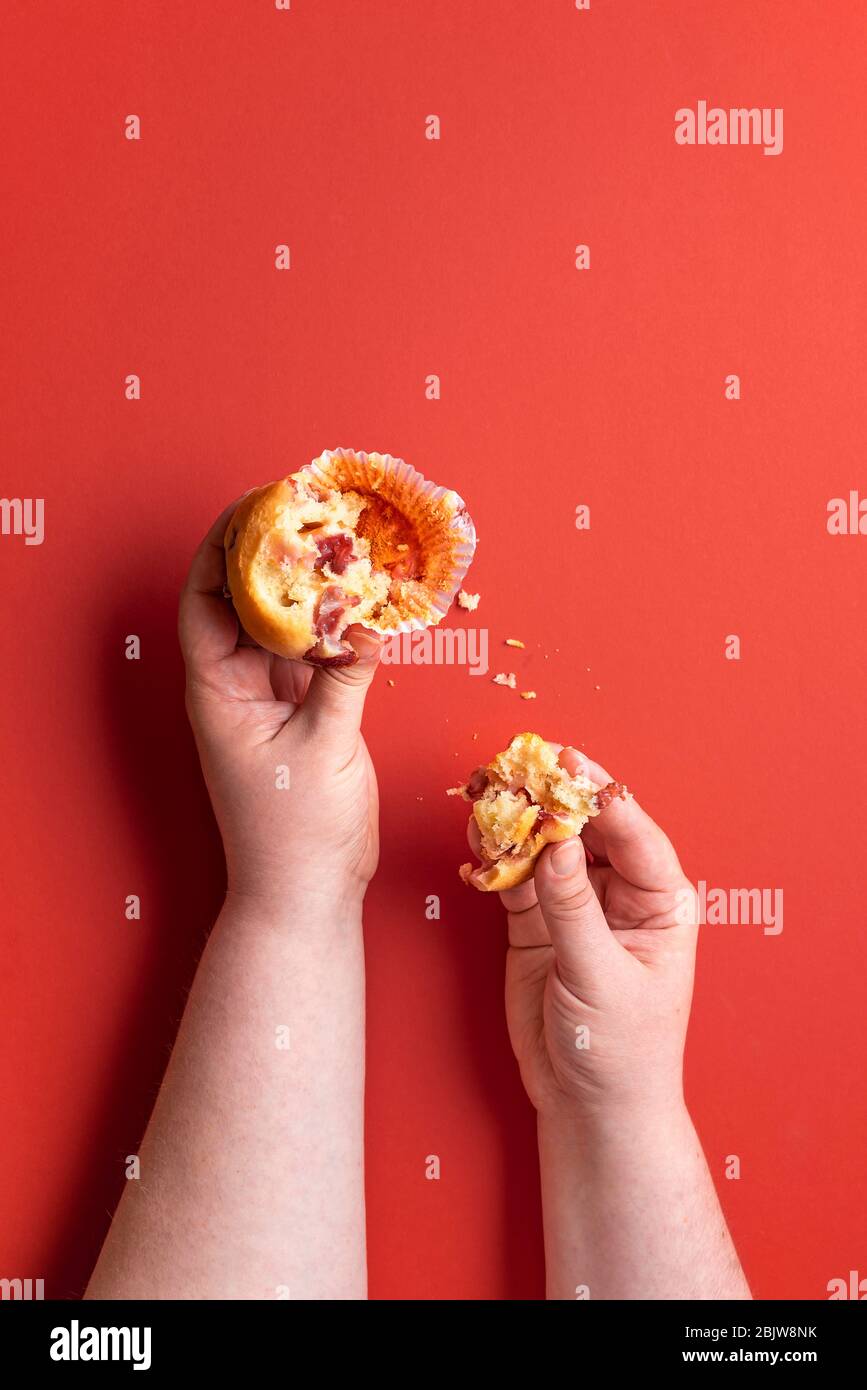 Strawberry muffin eaten by woman hands over a seamless red background ...