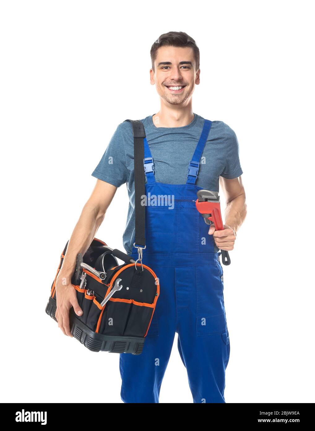 Young plumber in uniform with tool bag and pipe wrench on white ...