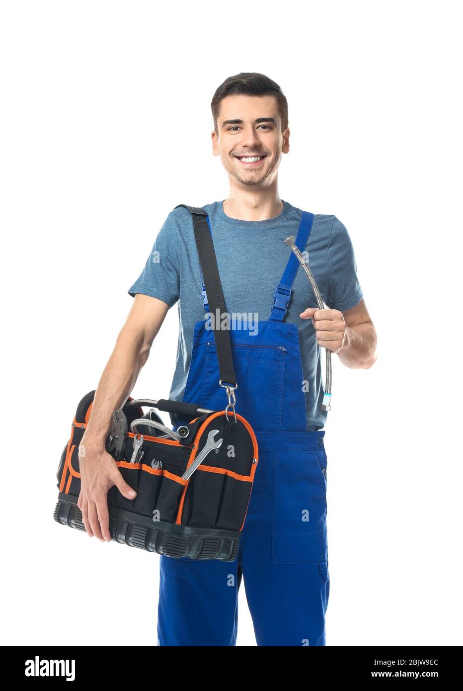 Young plumber in uniform with tool bag and flexible tube on white ...