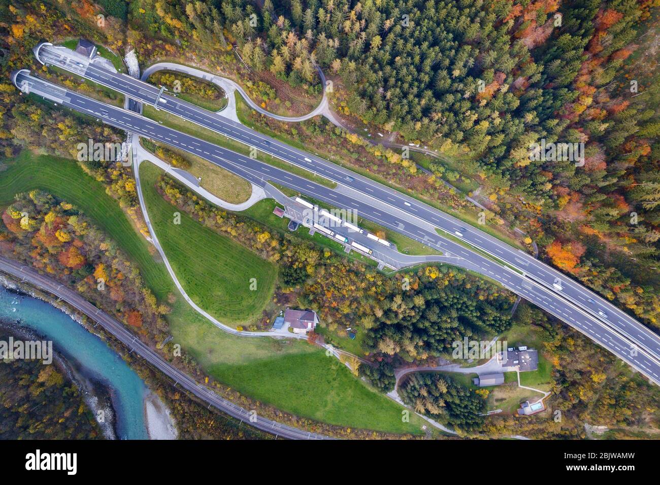 Top dawn aerial view of freeway speed road between yellow autumn forest trees and blue river ...