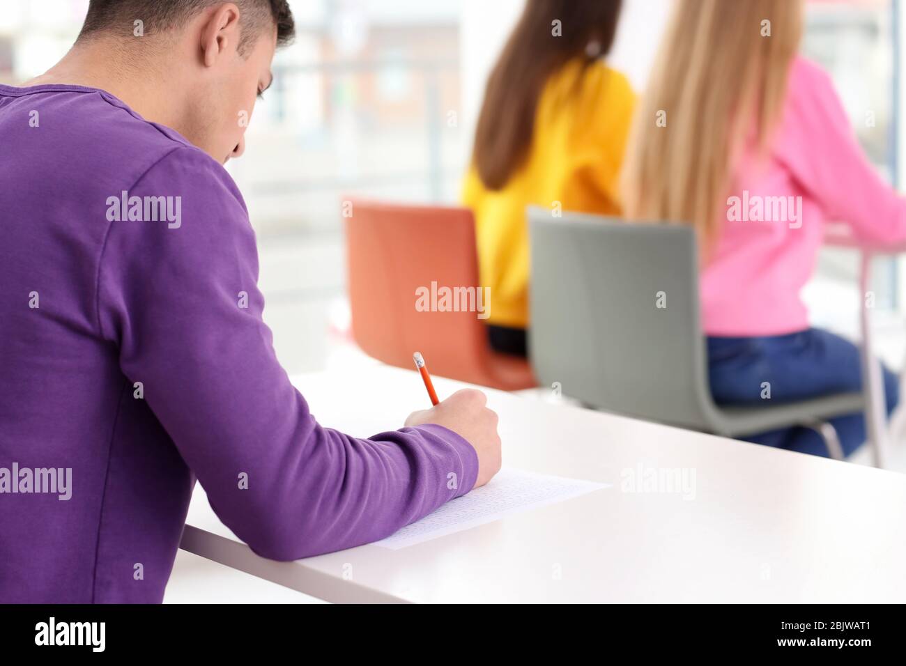 Student writing test to pass exam in classroom Stock Photo - Alamy