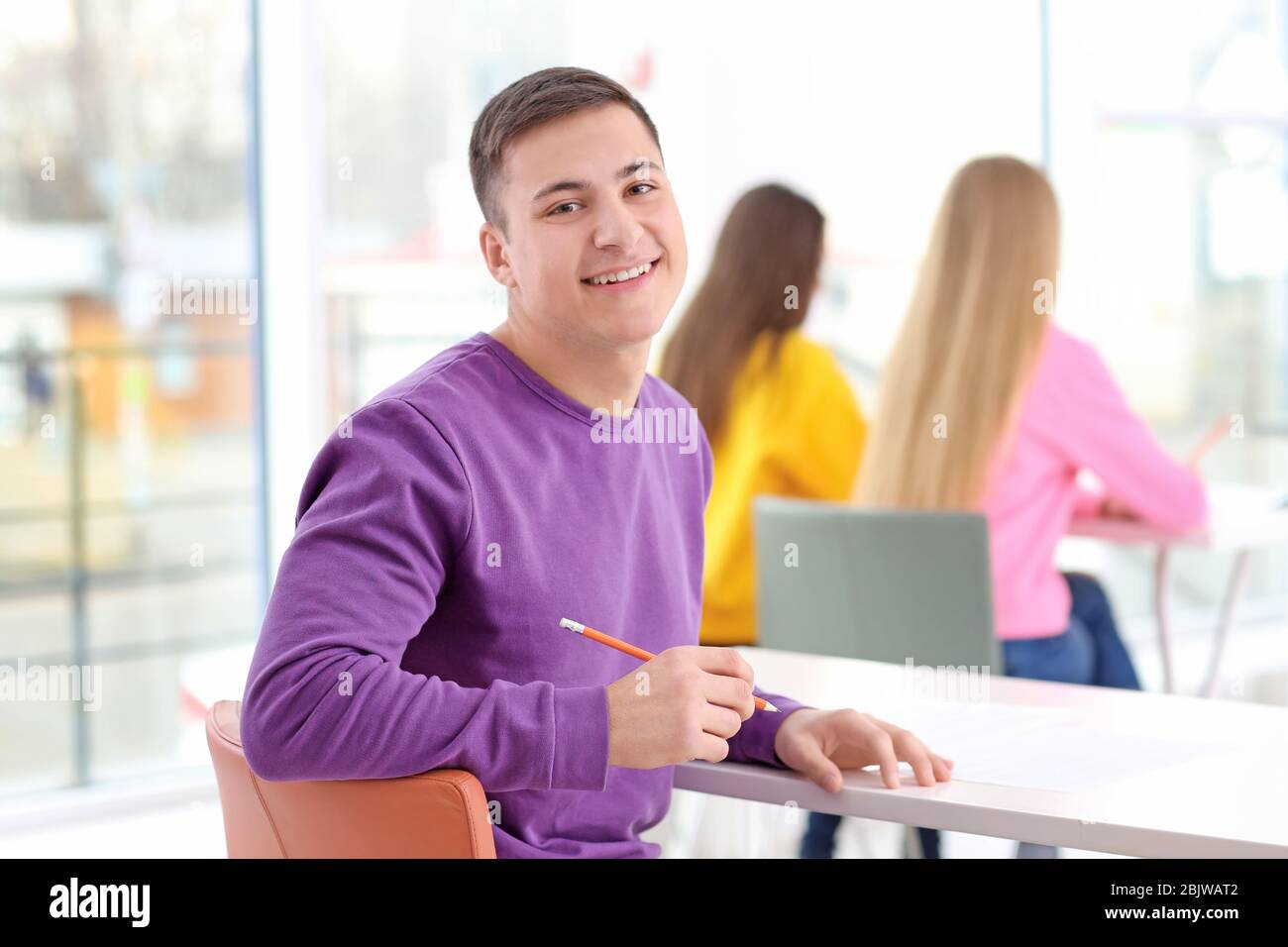 Student writing test to pass exam in classroom Stock Photo - Alamy