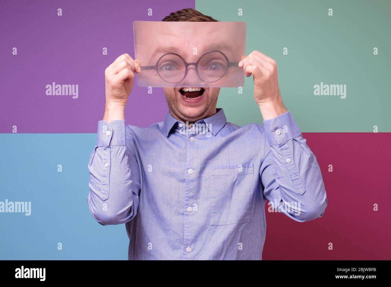 Happy funny man looking through a magnifying glass. Studio shot Stock ...