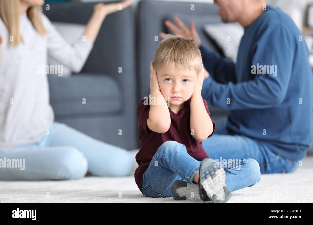 Sad little boy in room with quarreling parents. Family conflict Stock ...
