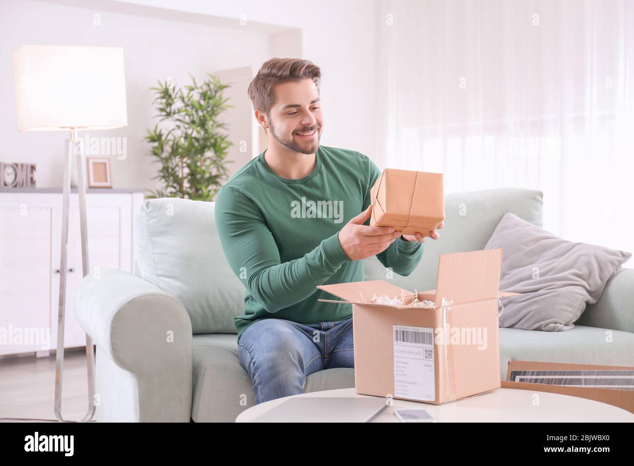 Young man unpacking parcel at home Stock Photo - Alamy