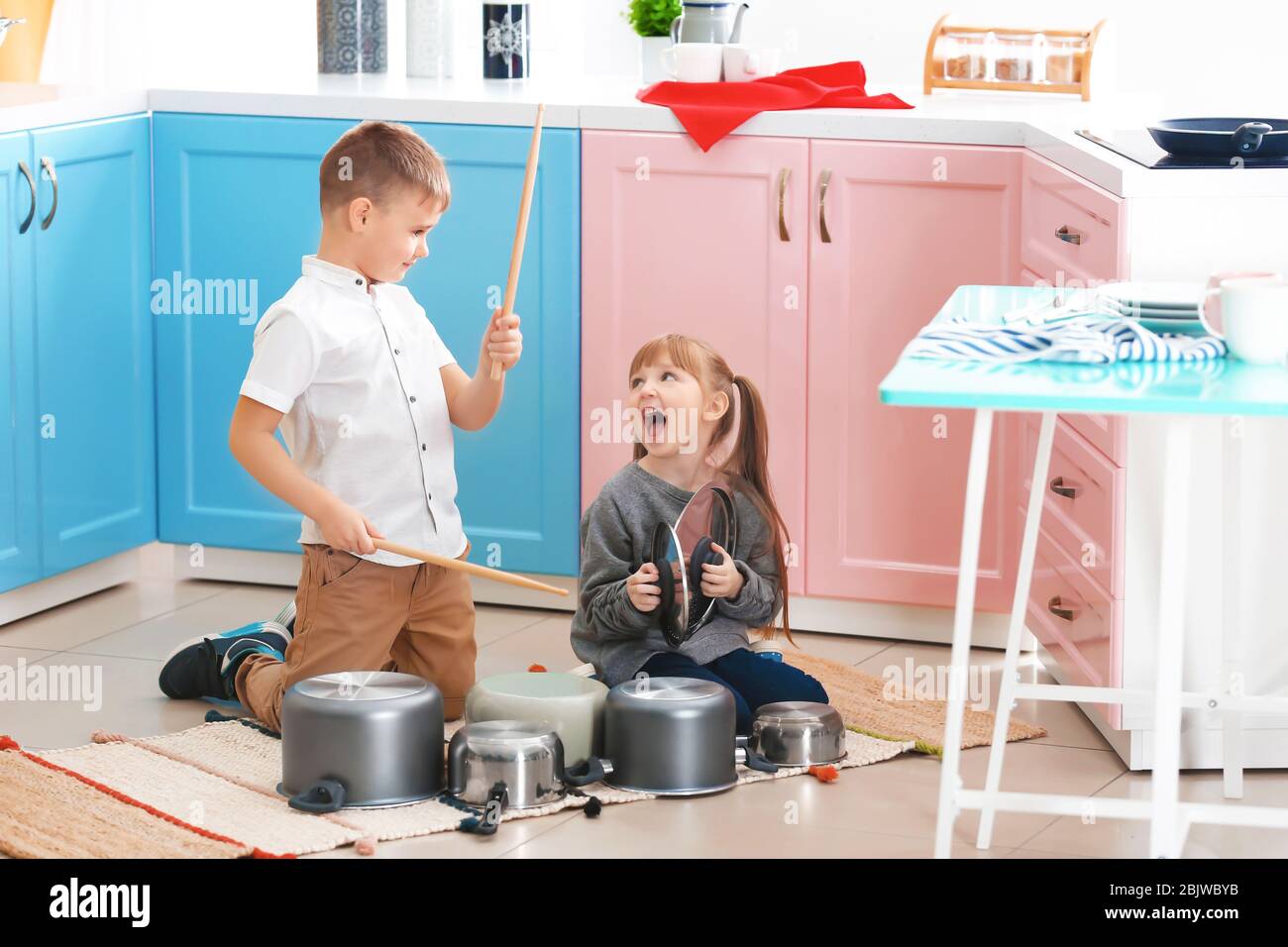 Cute little children playing with kitchenware as musical band at home ...