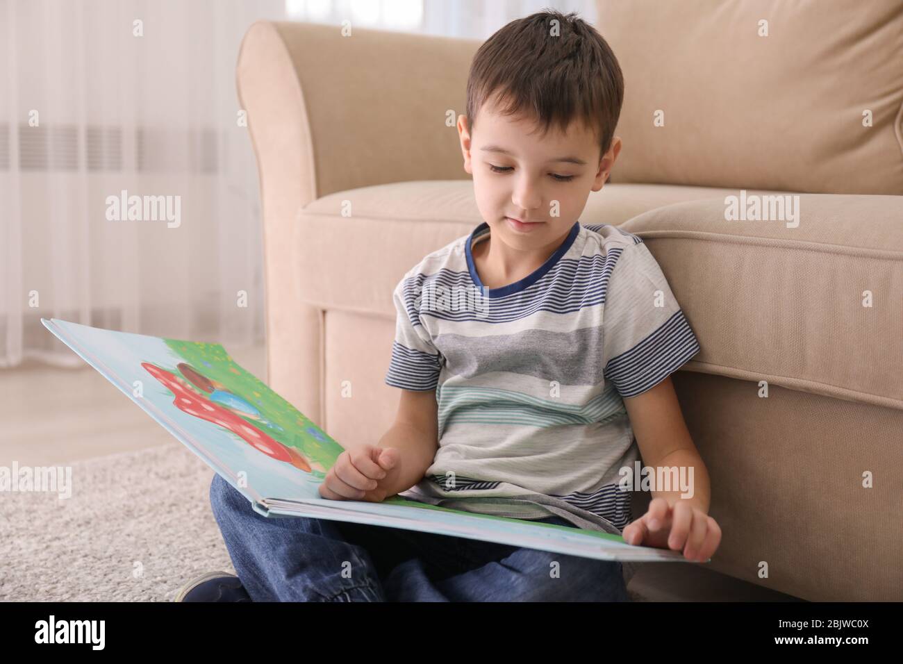 Cute little boy reading book at home Stock Photo - Alamy