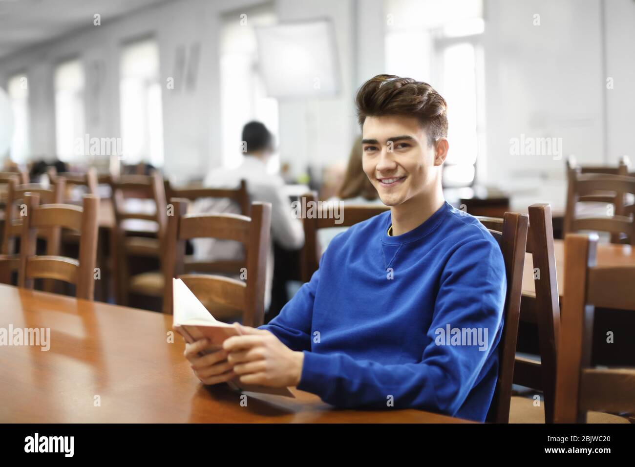 Student with book studying in library Stock Photo - Alamy