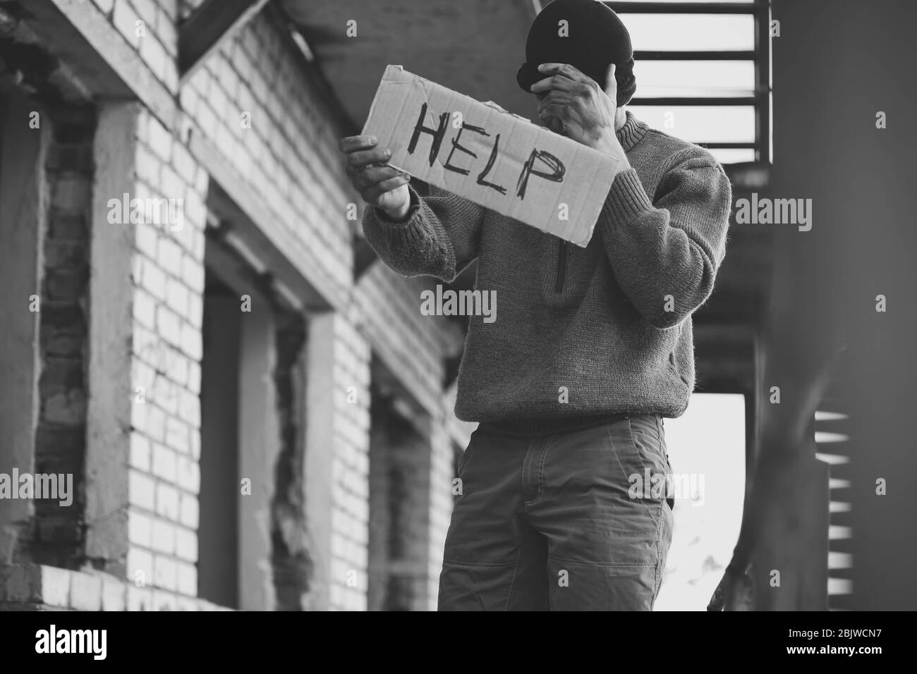 Homeless poor man holding piece of cardboard with word HELP outdoors ...