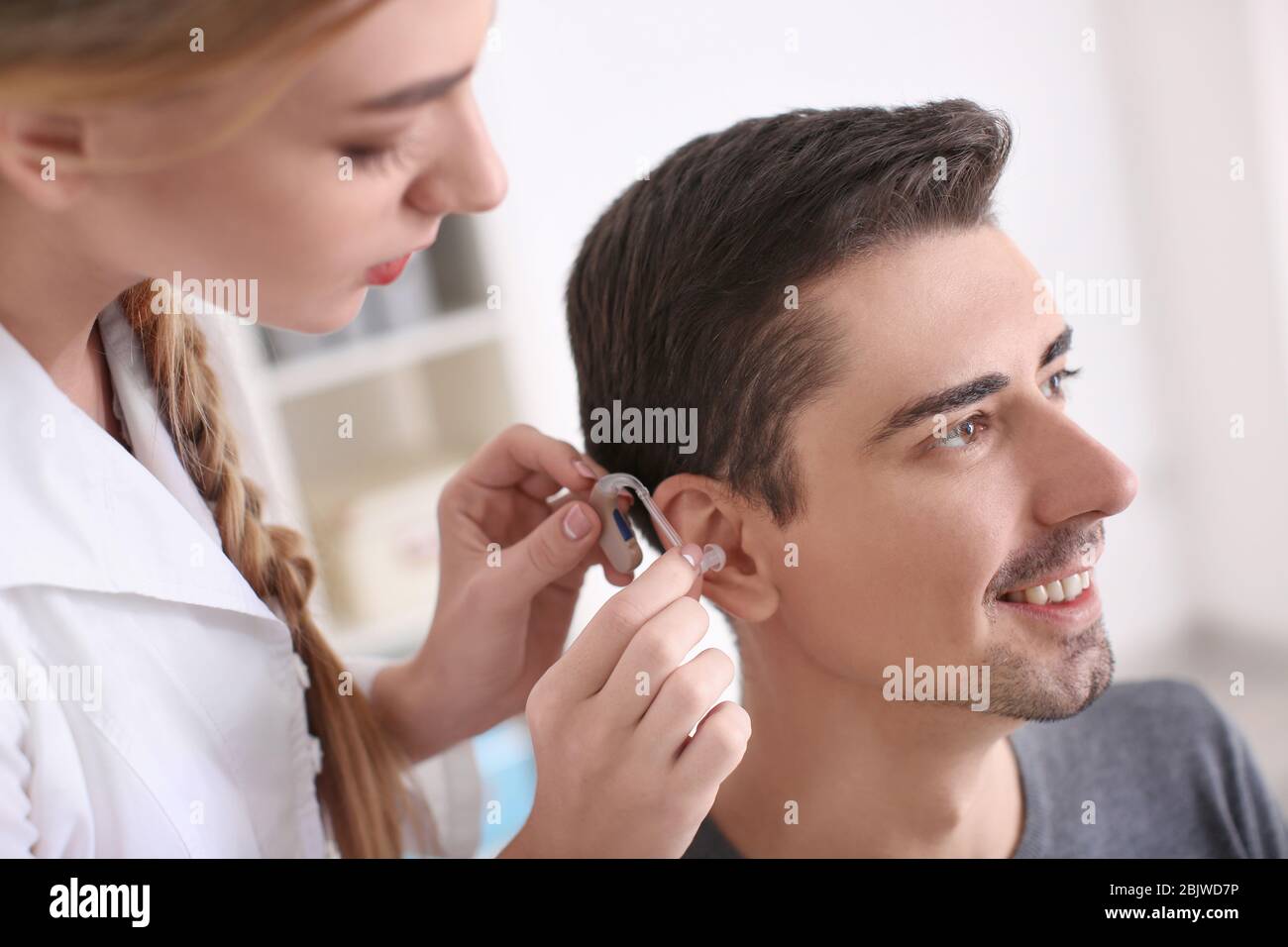Otolaryngologist putting hearing aid in patient's ear in hospital Stock ...