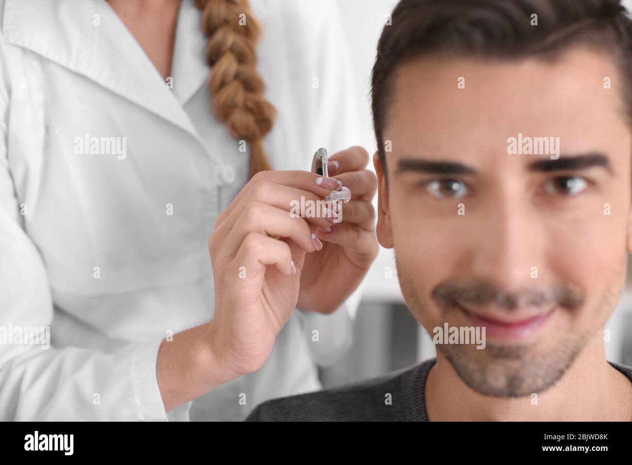Otolaryngologist putting hearing aid in patient's ear in hospital Stock ...
