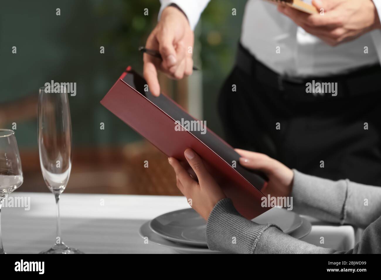 Waiter showing menu to client in restaurant Stock Photo - Alamy