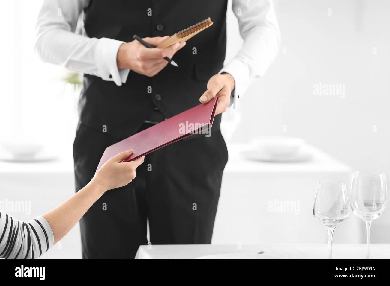 Waiter giving menu to client in restaurant Stock Photo - Alamy