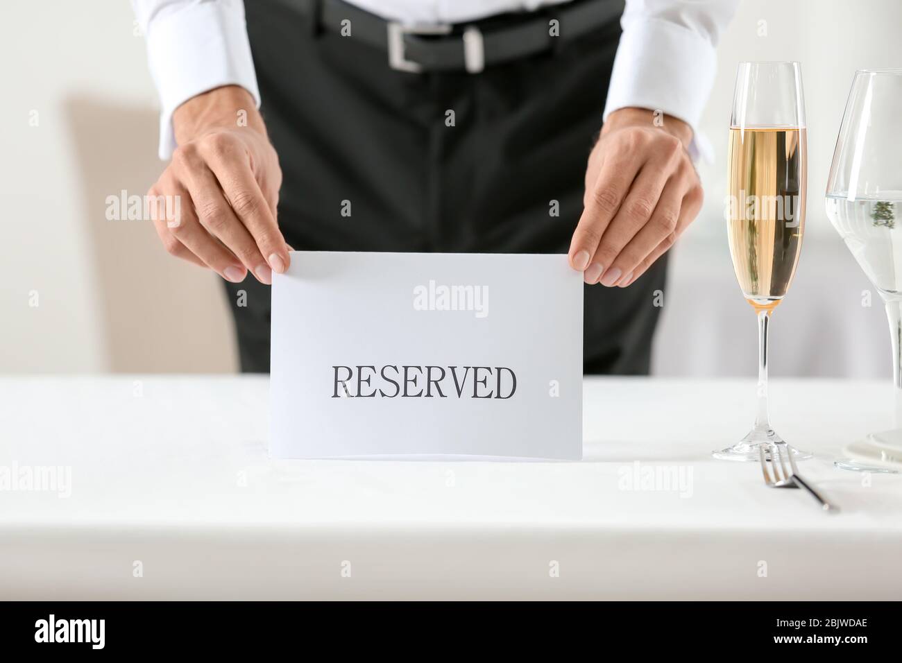 Waiter with sign RESERVED in restaurant Stock Photo - Alamy