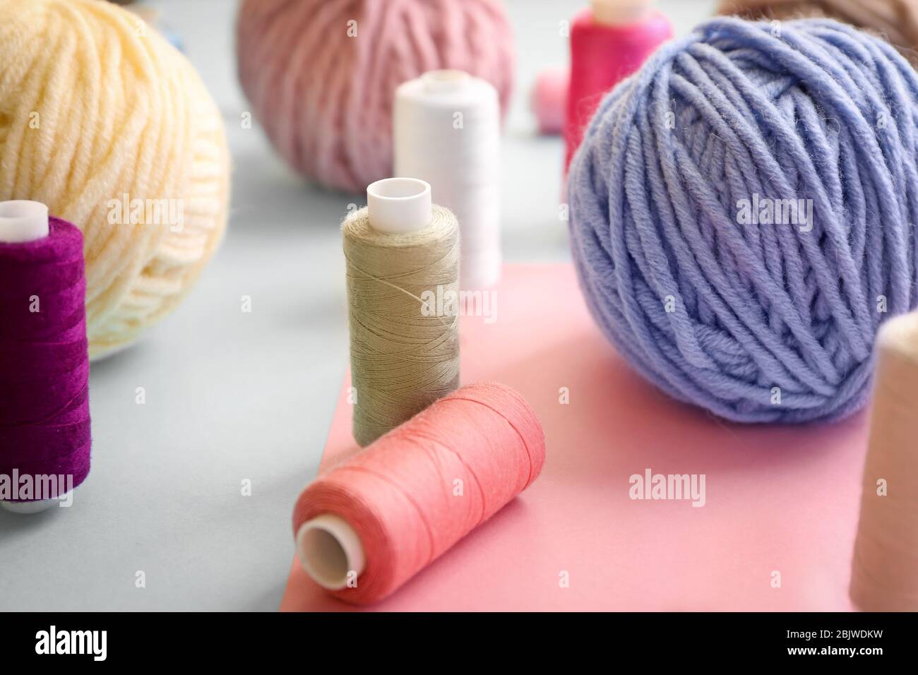 Sewing and woolen threads on color background Stock Photo - Alamy