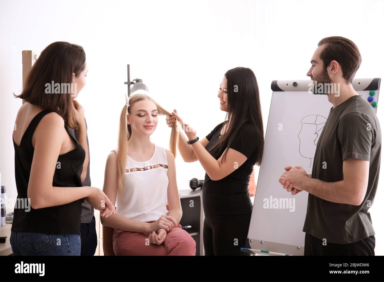 Professional hairdresser and trainees working with client in salon ...