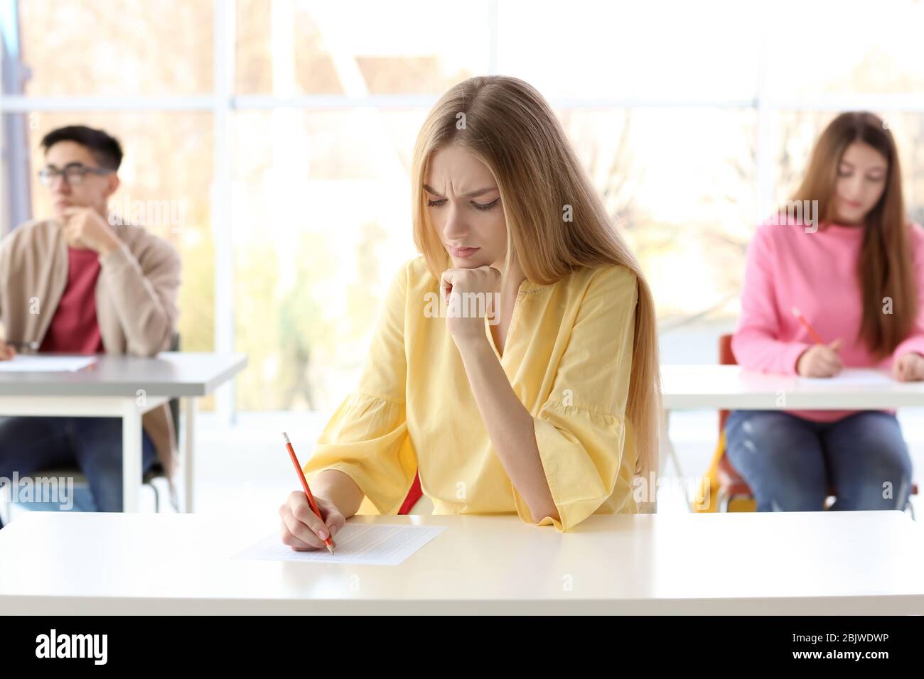 Female student taking exam in classroom Stock Photo - Alamy