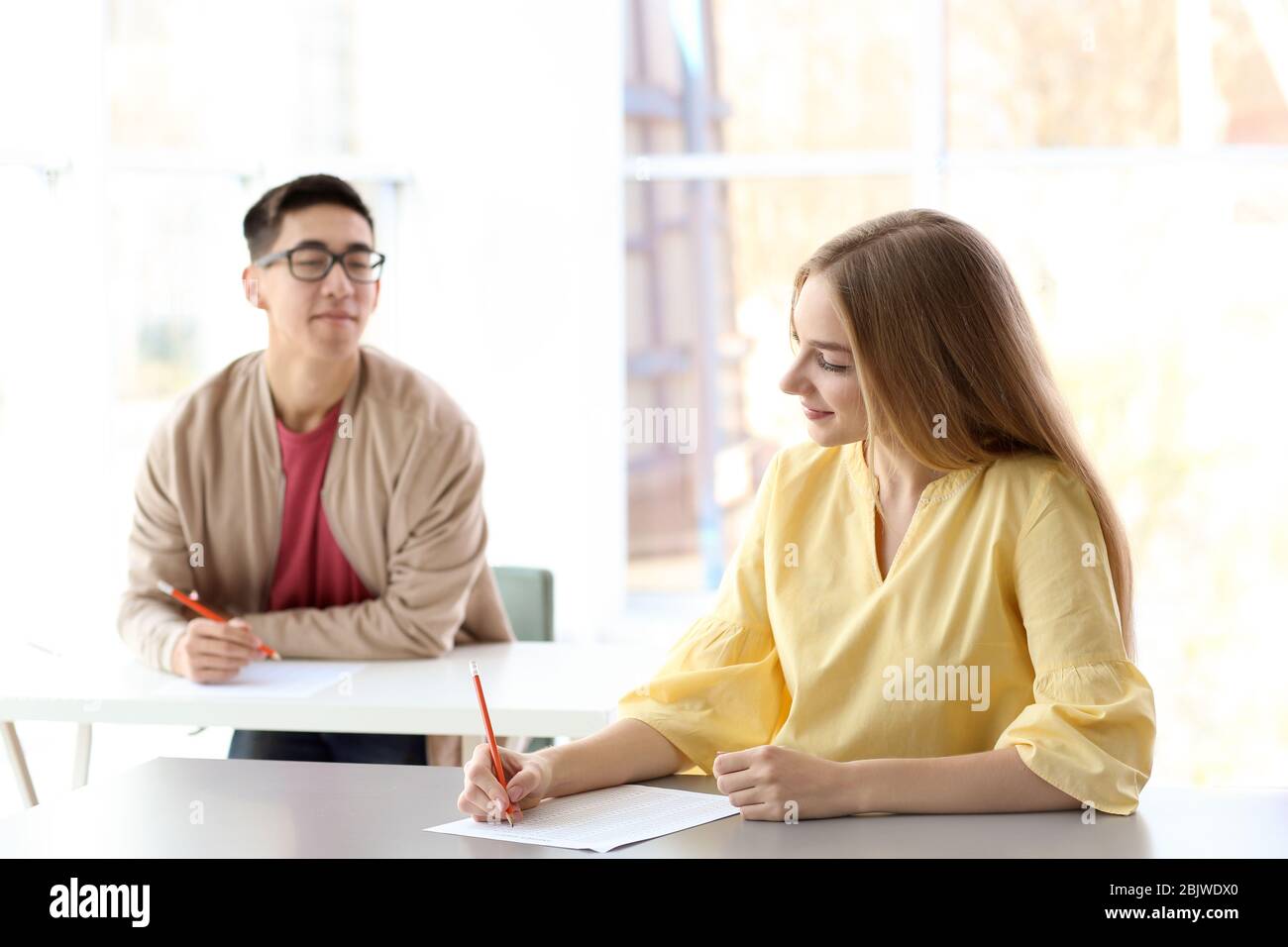 Asian student trying to copy answers of classmate at exam Stock Photo ...