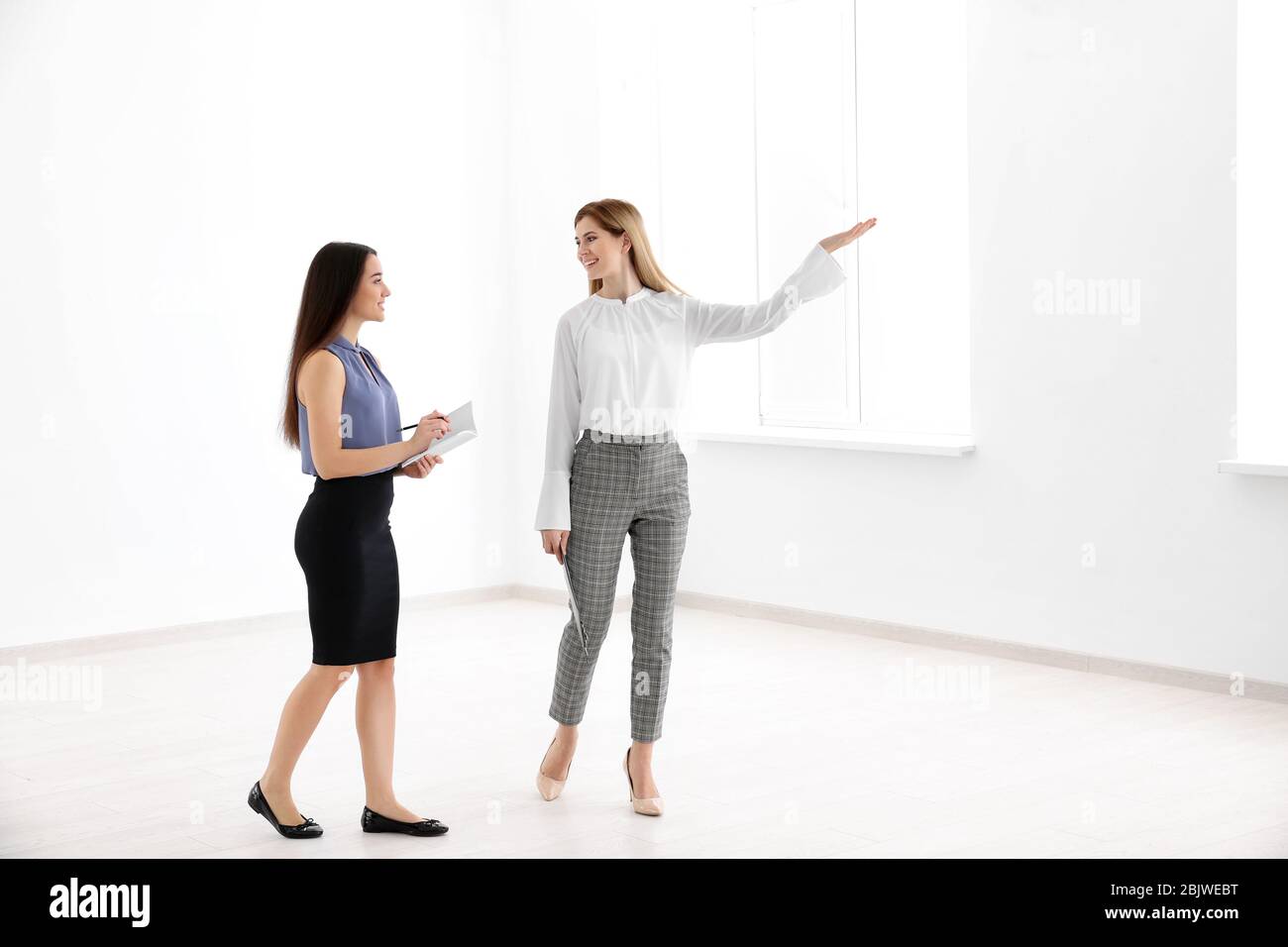 Real estate agent with trainee in empty apartment Stock Photo - Alamy