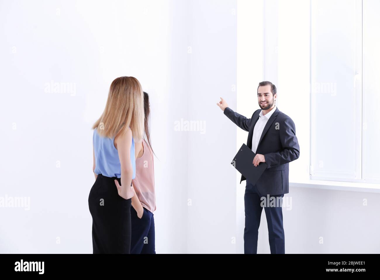 Real estate agent with trainee showing apartment to client Stock Photo ...