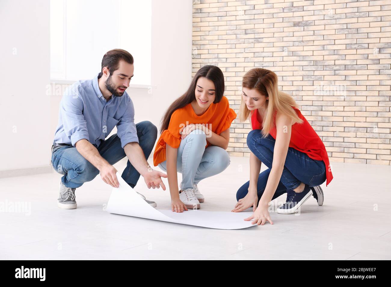 Real estate agent with trainee showing plan of apartment to client ...