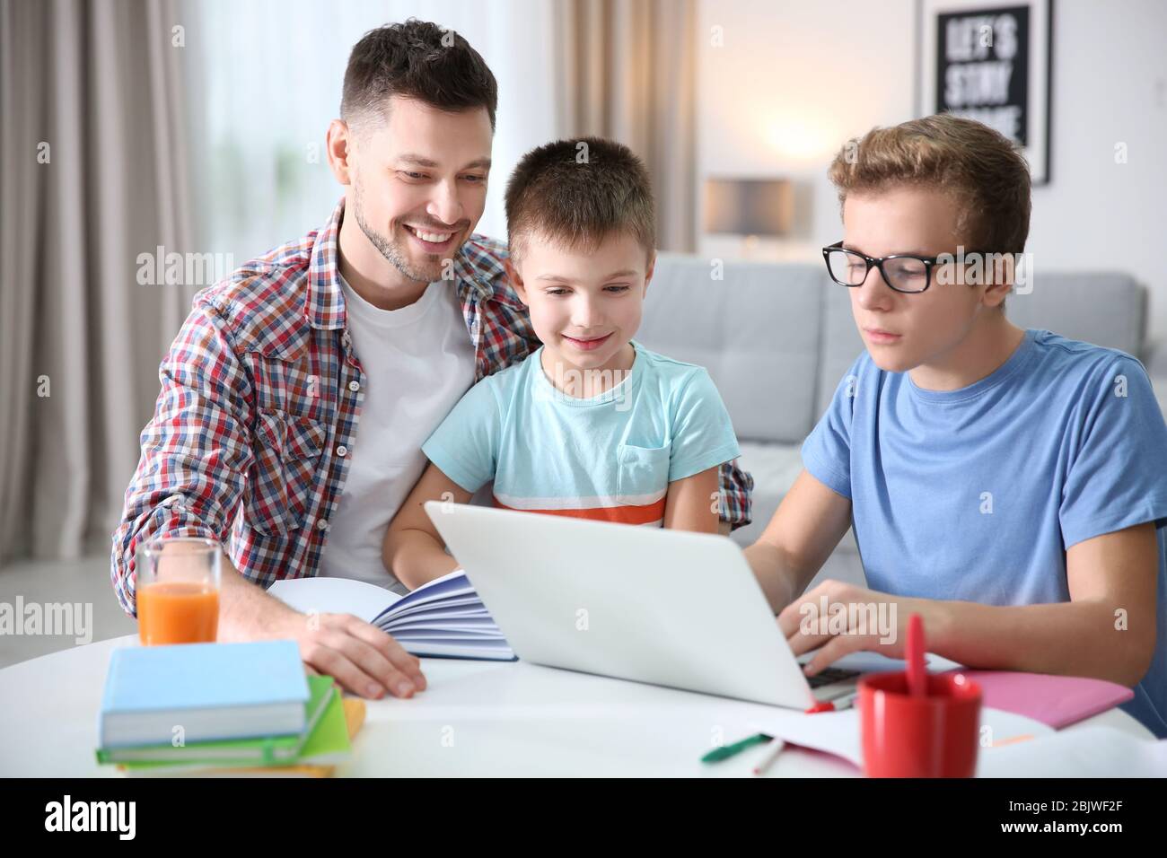 Children with father doing homework at home Stock Photo - Alamy