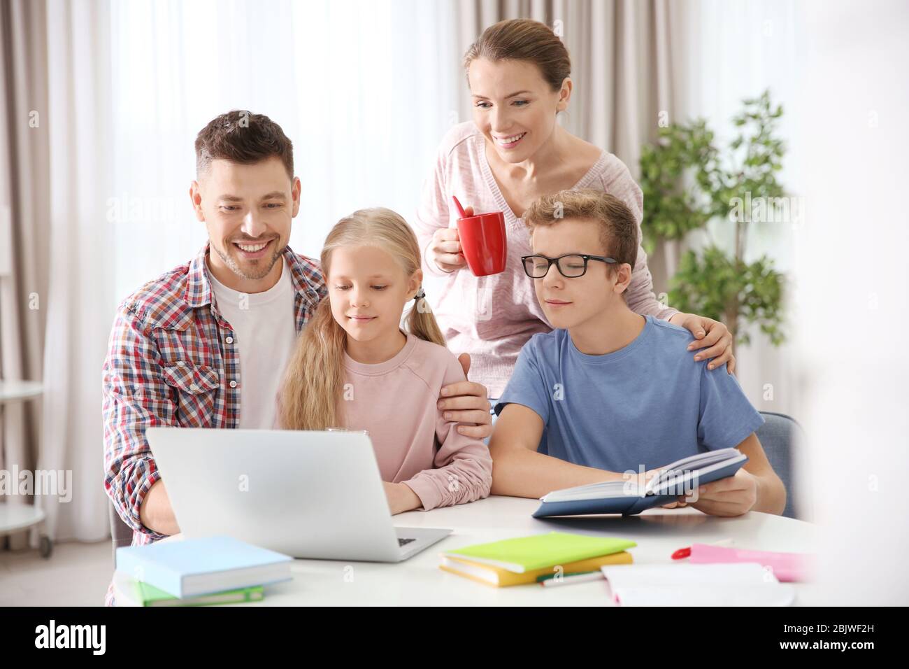 Children with parents doing homework at home Stock Photo - Alamy