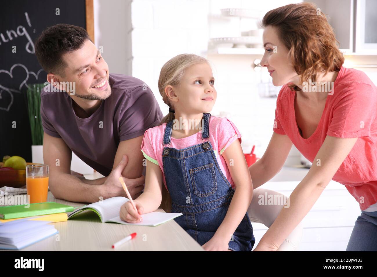 Little girl with parents doing homework at home Stock Photo - Alamy