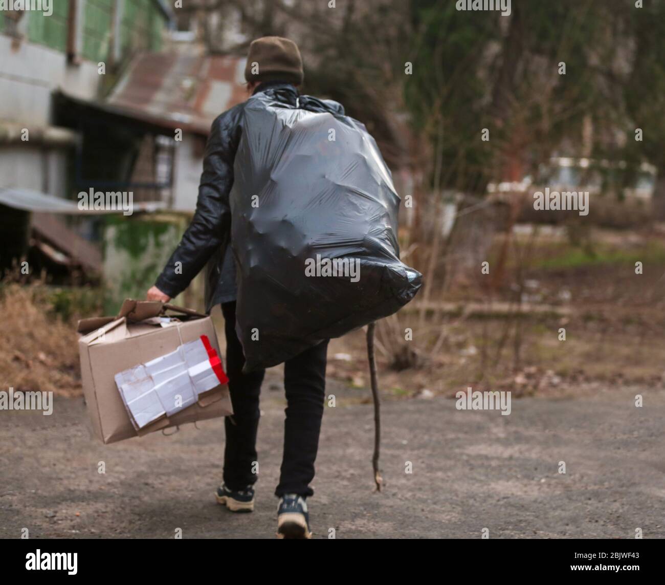 Poor man with packages of garbage outdoors Stock Photo - Alamy