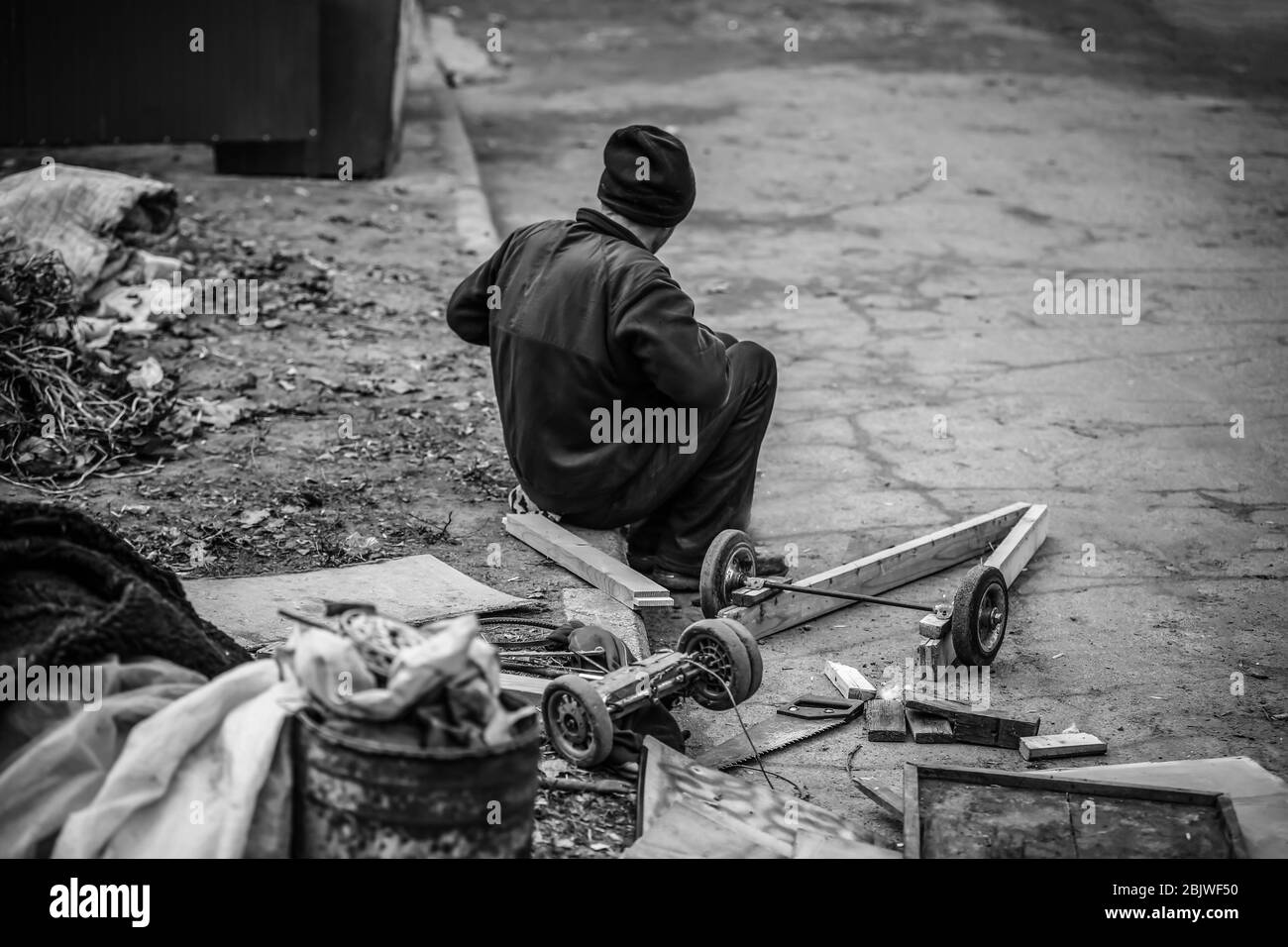 Poor man sitting on sidewalk near heap of garbage outdoors Stock Photo ...