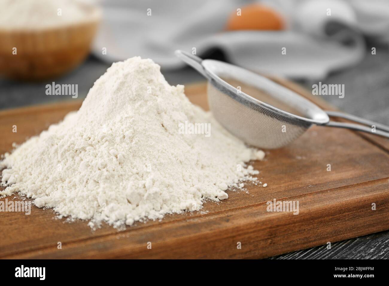 Heap of wheat flour and sieve on wooden board Stock Photo - Alamy