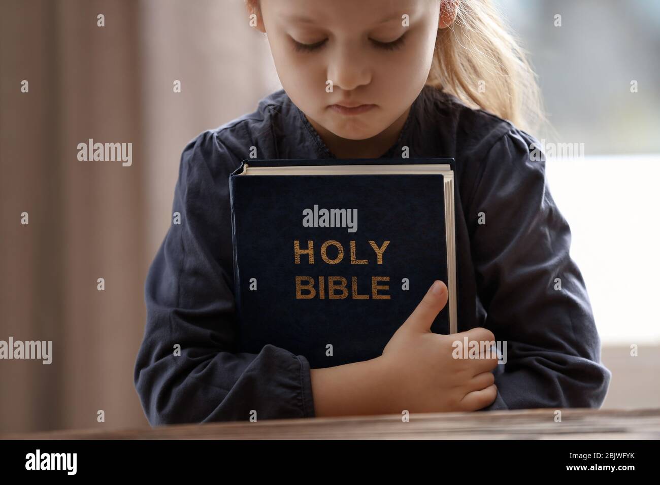Religious Christian girl with Bible indoors Stock Photo - Alamy