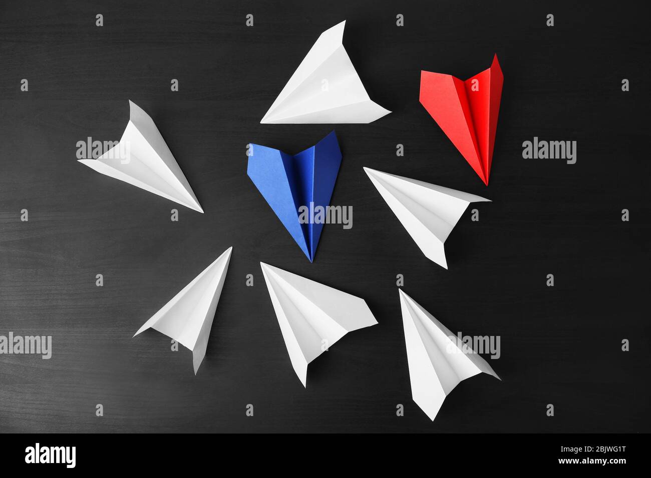 Blue and red paper planes among white ones on dark background ...