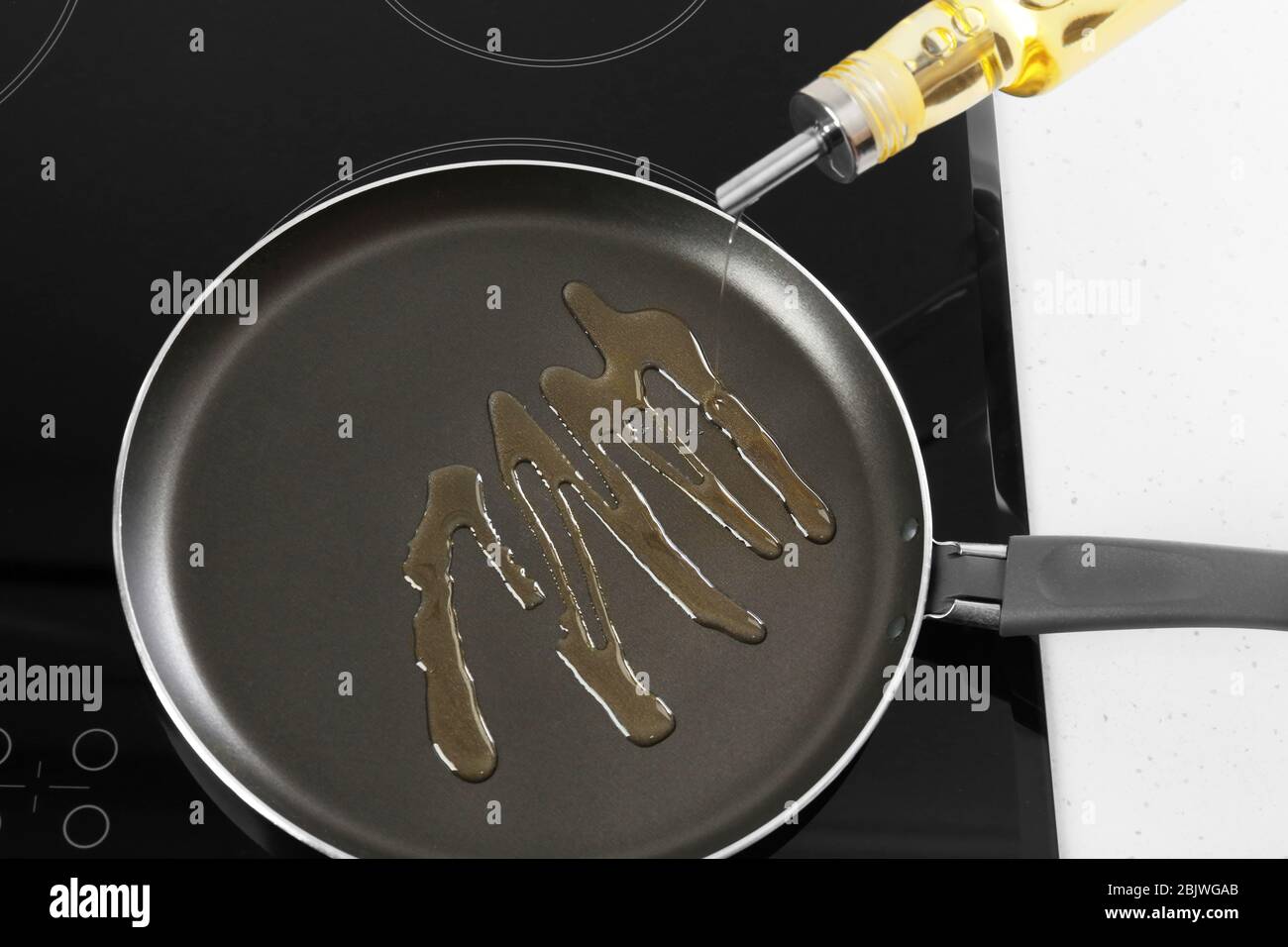 Pouring cooking oil from bottle into frying pan on stove Stock Photo ...