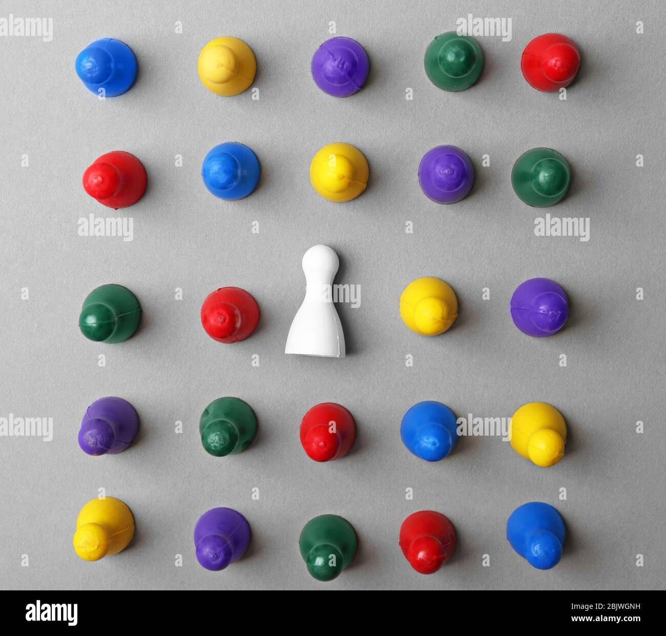 Board game figures and one different on grey background Stock Photo - Alamy
