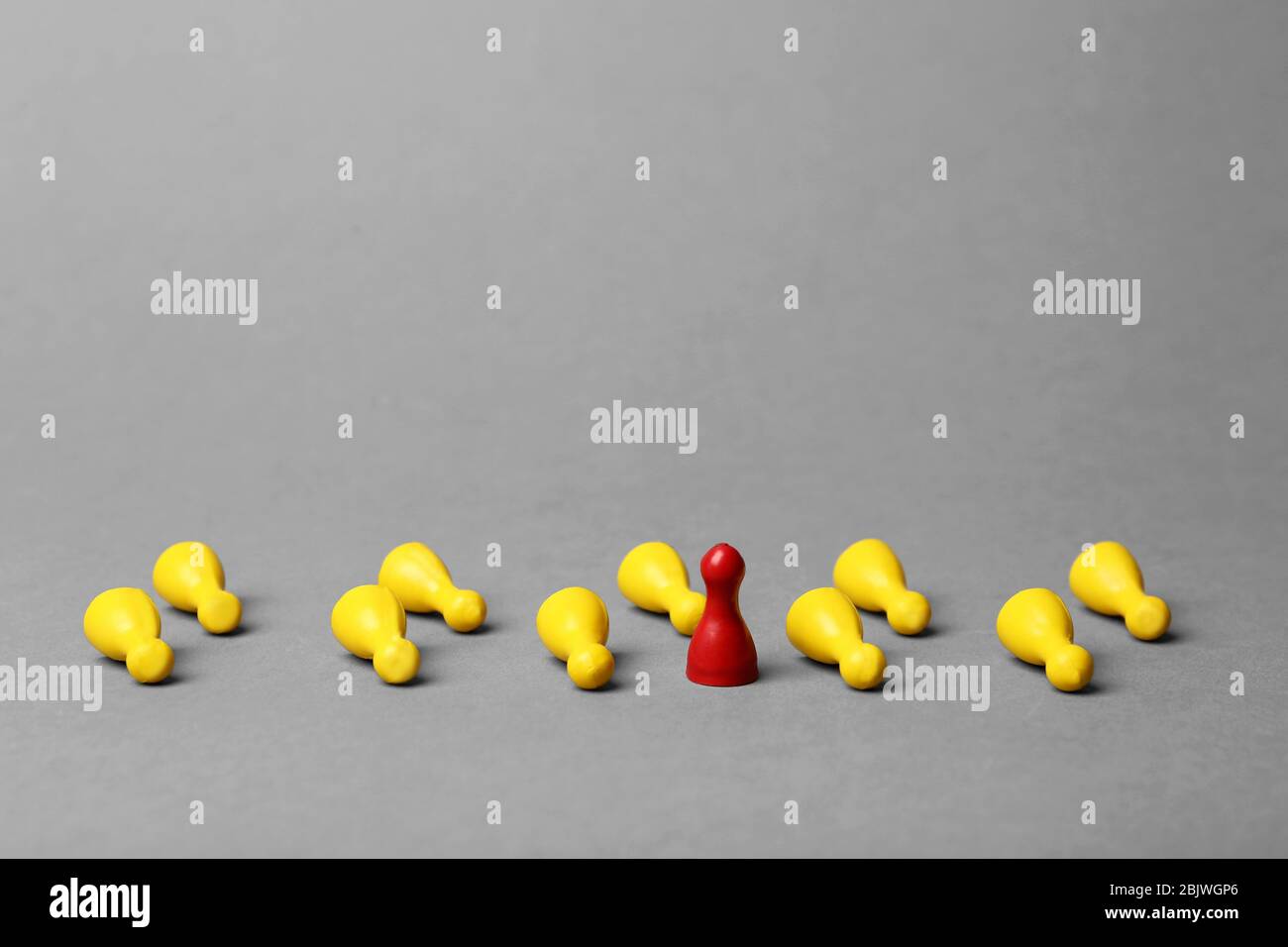Board game figures and one different on grey background Stock Photo - Alamy