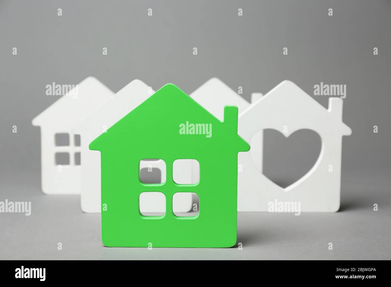 House figures and one different on grey background Stock Photo - Alamy